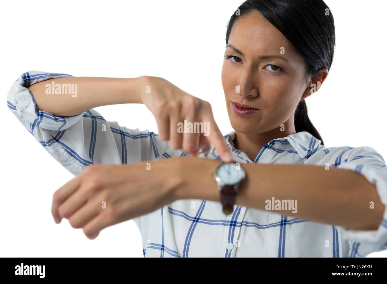 Female executive pointing at her wristwatch against white background ...