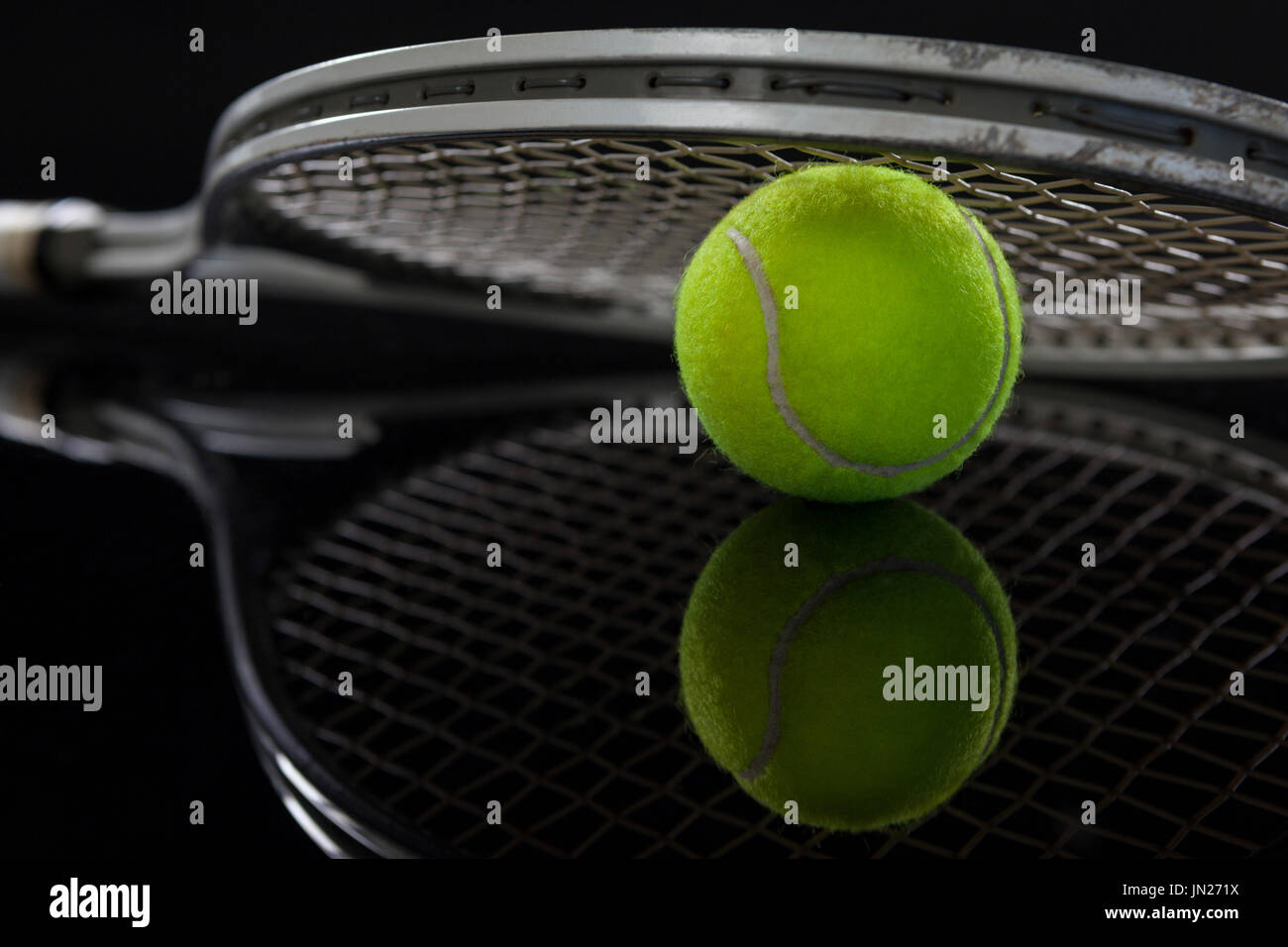 Close up of racket on fluorescent yellow tennis ball with reflection ...