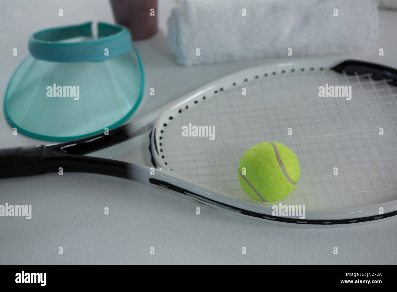 High angle view of tennis ball on racket by sun visor against white ...