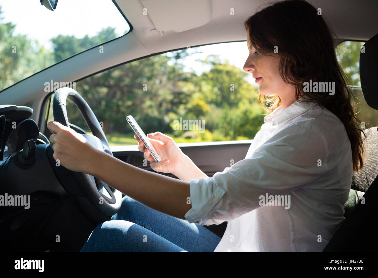 Beautiful woman using mobile phone while driving a car Stock Photo - Alamy
