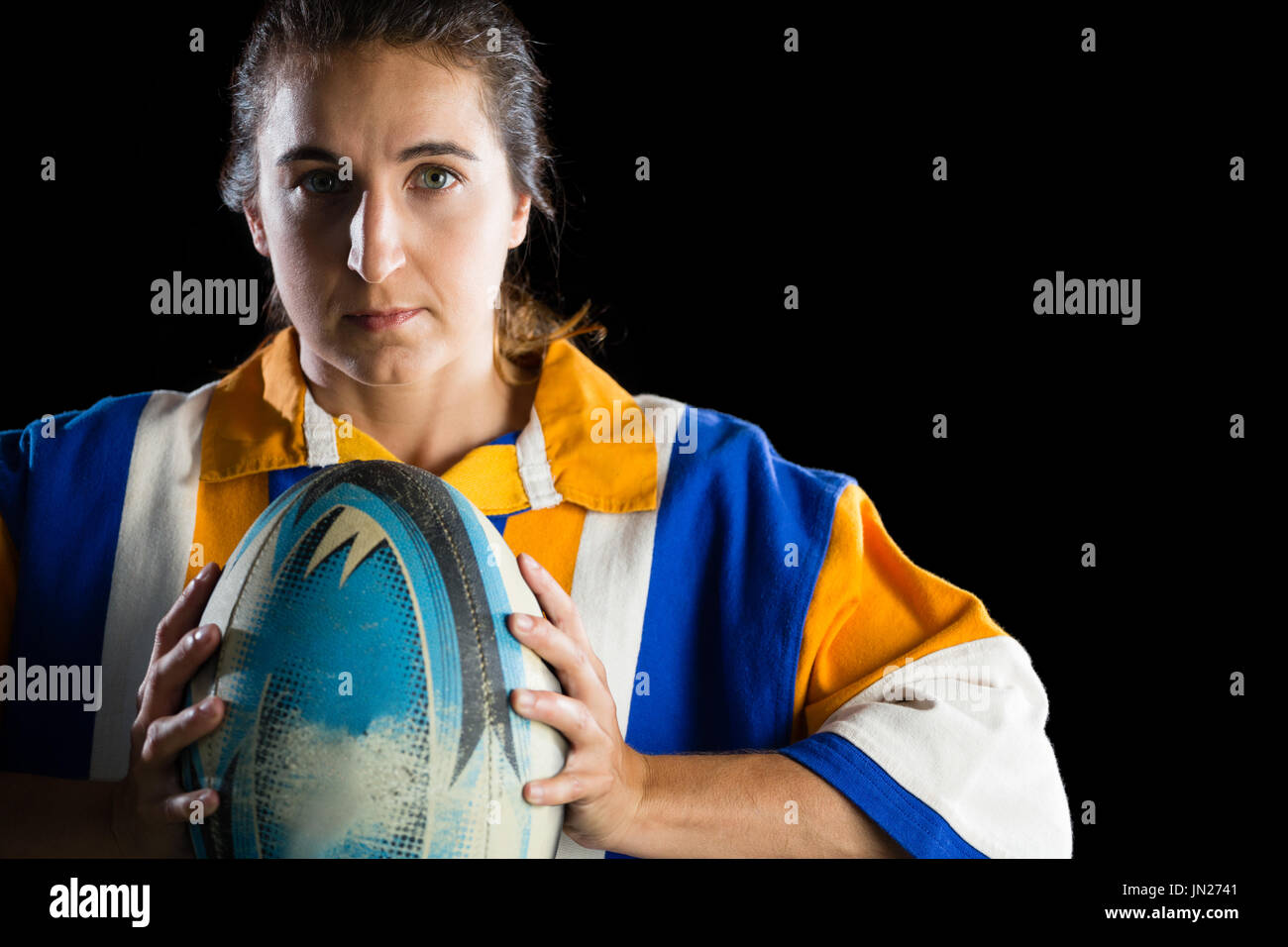 Close up portrait of female rugby player with ball standing against ...