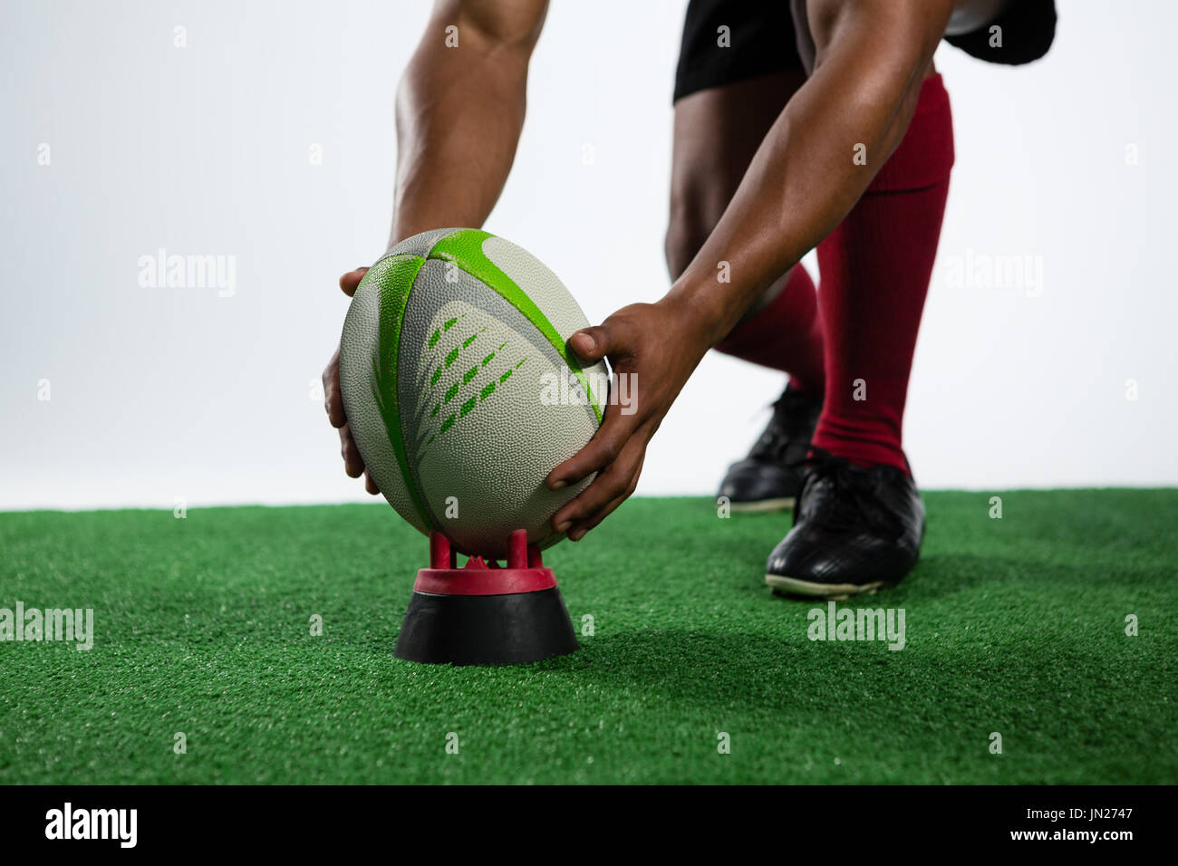 Low section of sportsman keeping rugby ball on tee while playing ...