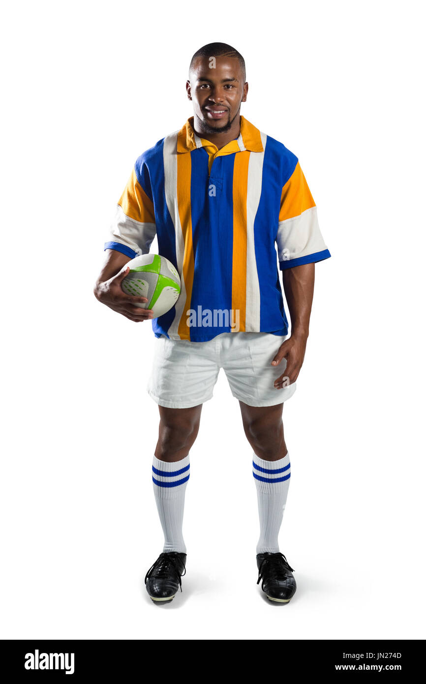 Portrait of happy rugby player holding ball while standing against ...