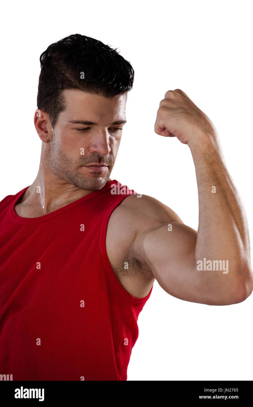 Male athlete flexing muscles while standing against white background ...
