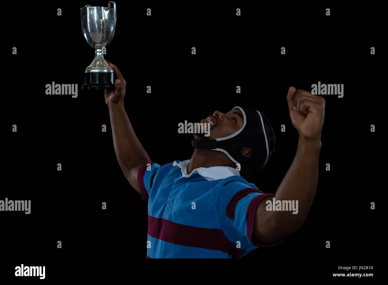 Happy rugby player holding trophy against black background Stock Photo ...