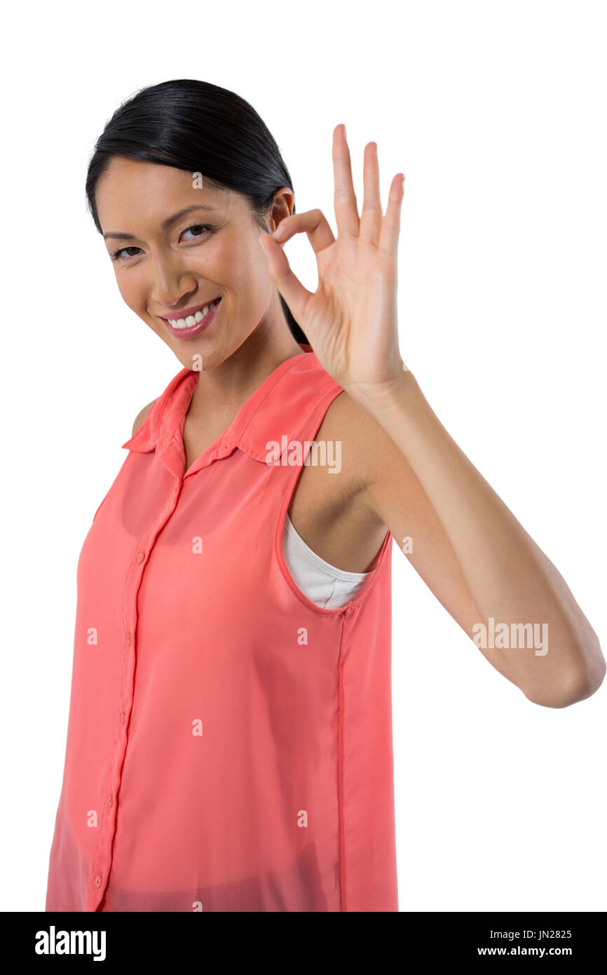 Portrait of smiling woman gesturing okay hand sign against white ...