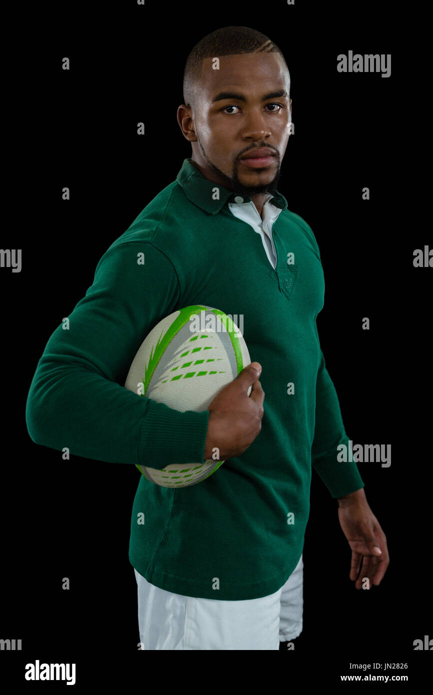 Portrait of confident male player with rugby ball standing against ...