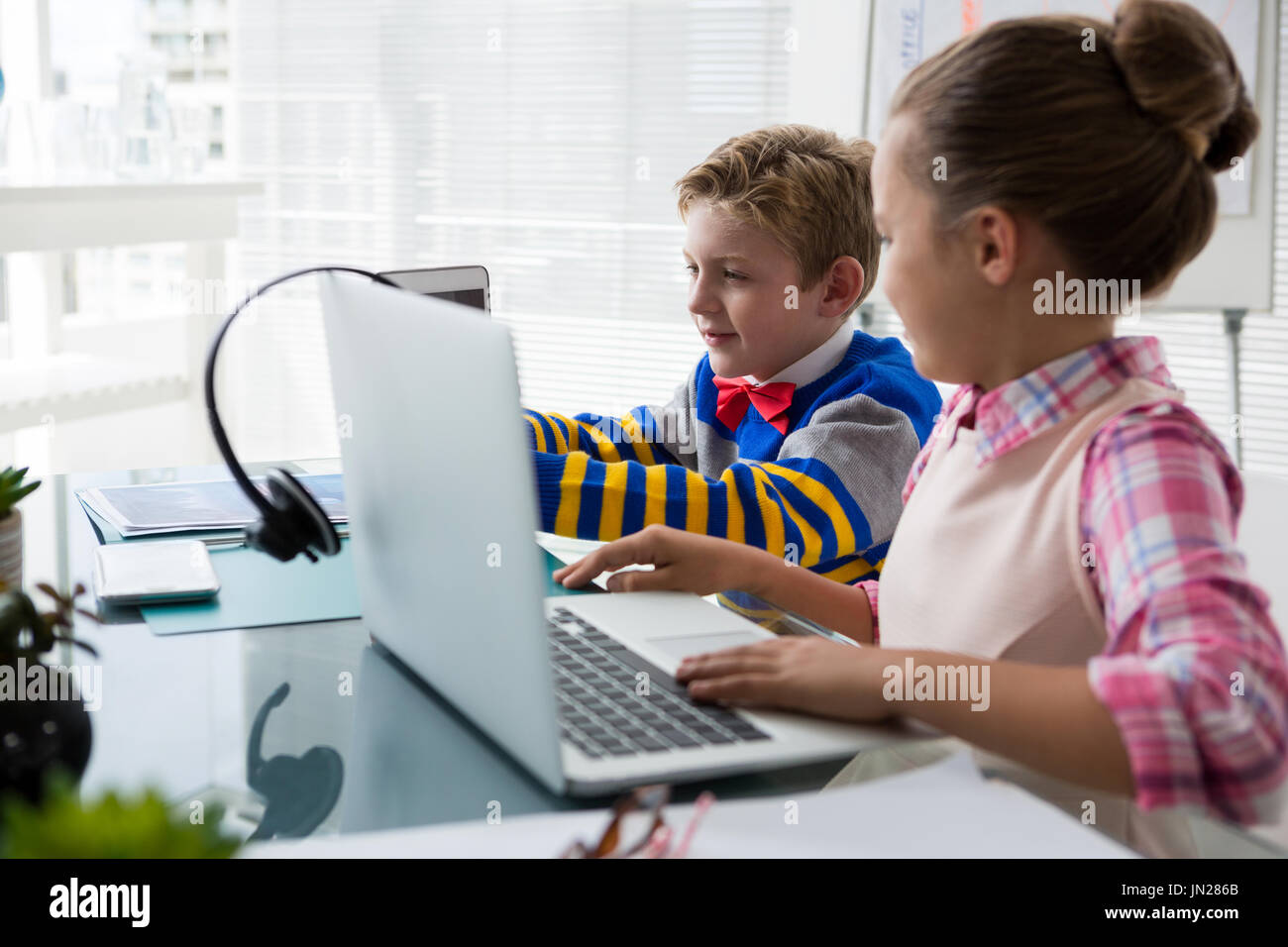 Kids as business executive interacting while using laptop in office ...