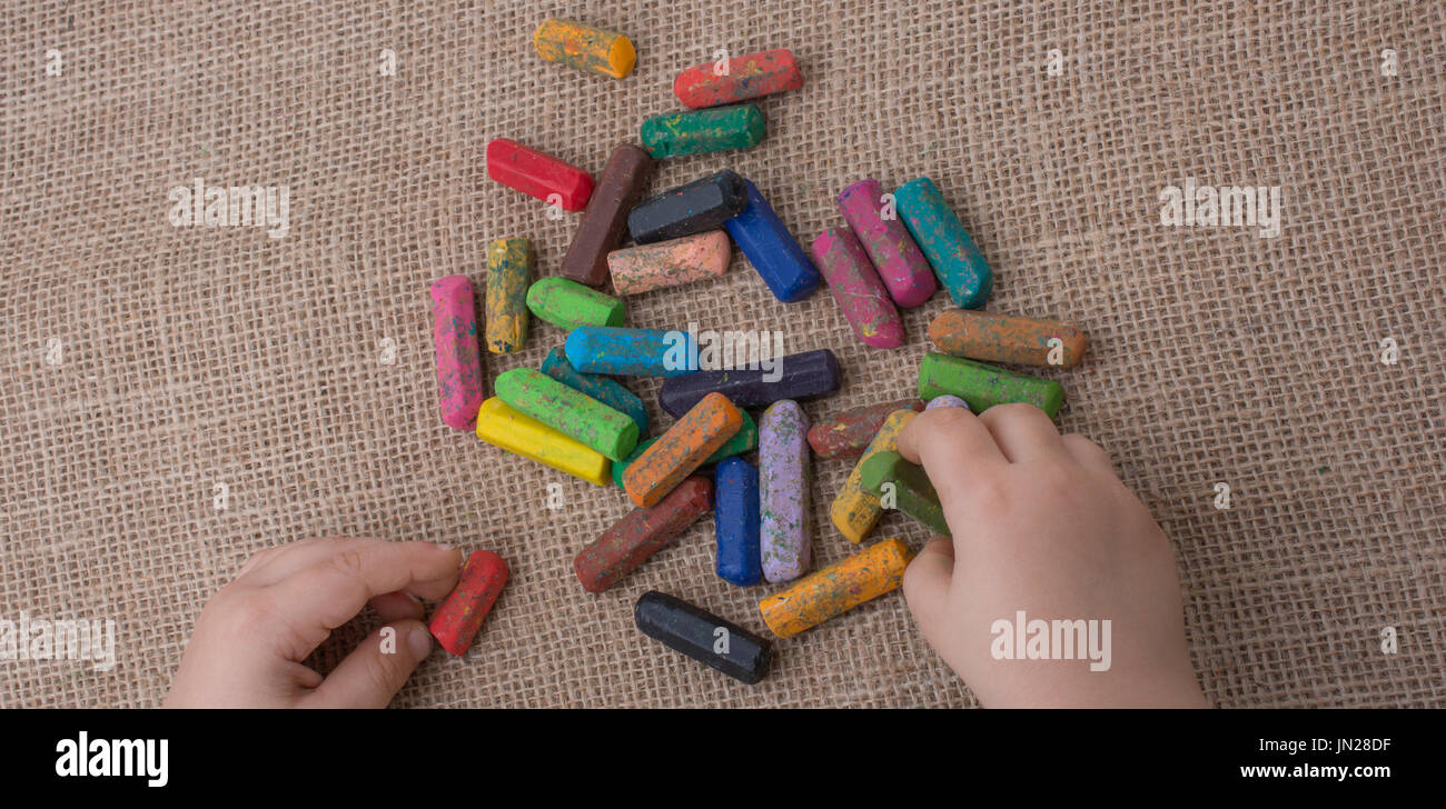 Used color crayons and a toddlers hand holding one Stock Photo - Alamy