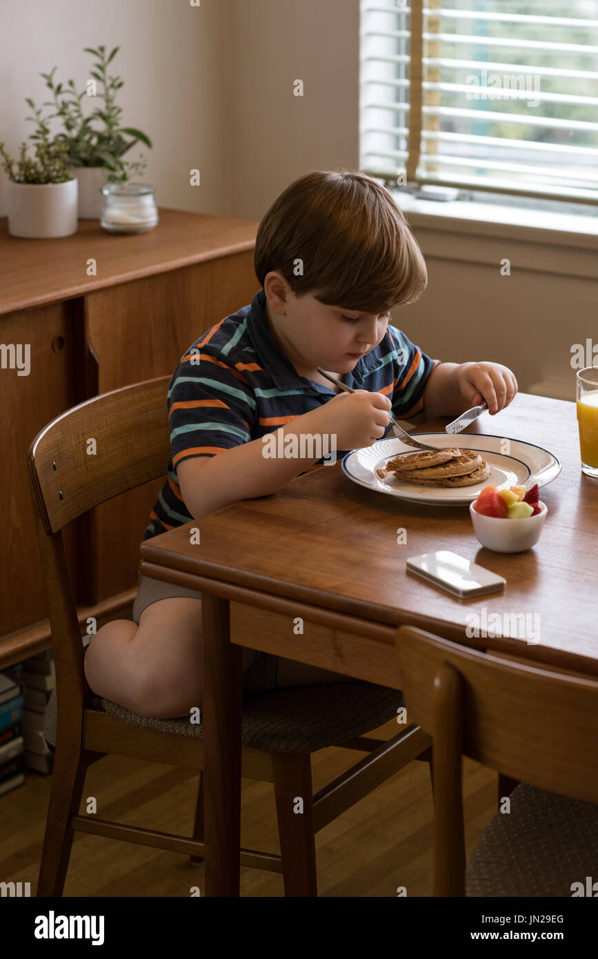 Cute boy having breakfast at table Stock Photo - Alamy