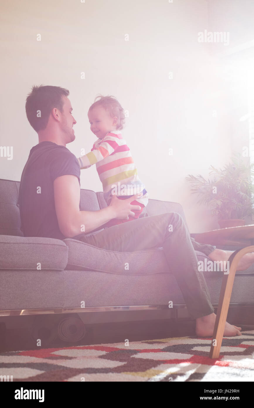 Side view of playful father with daughter on sofa at home Stock Photo ...