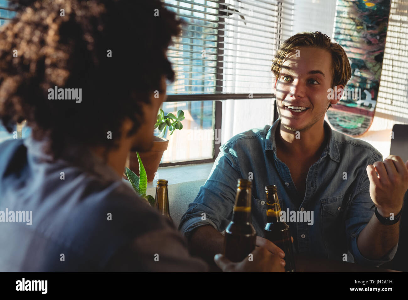 Friends interacting while enjoying the drinks at the bar Stock Photo ...