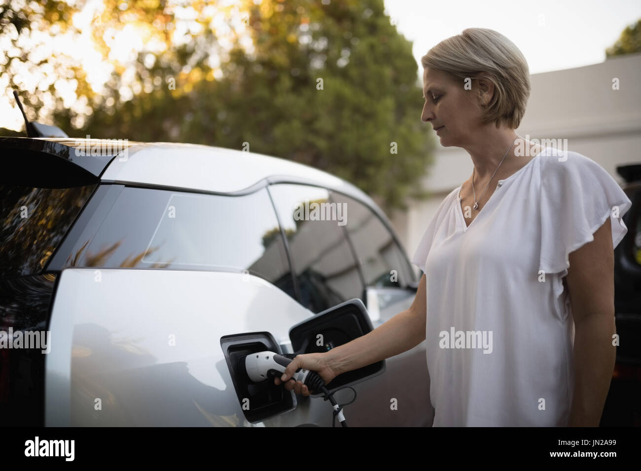 Woman charging electric car in street Stock Photo - Alamy