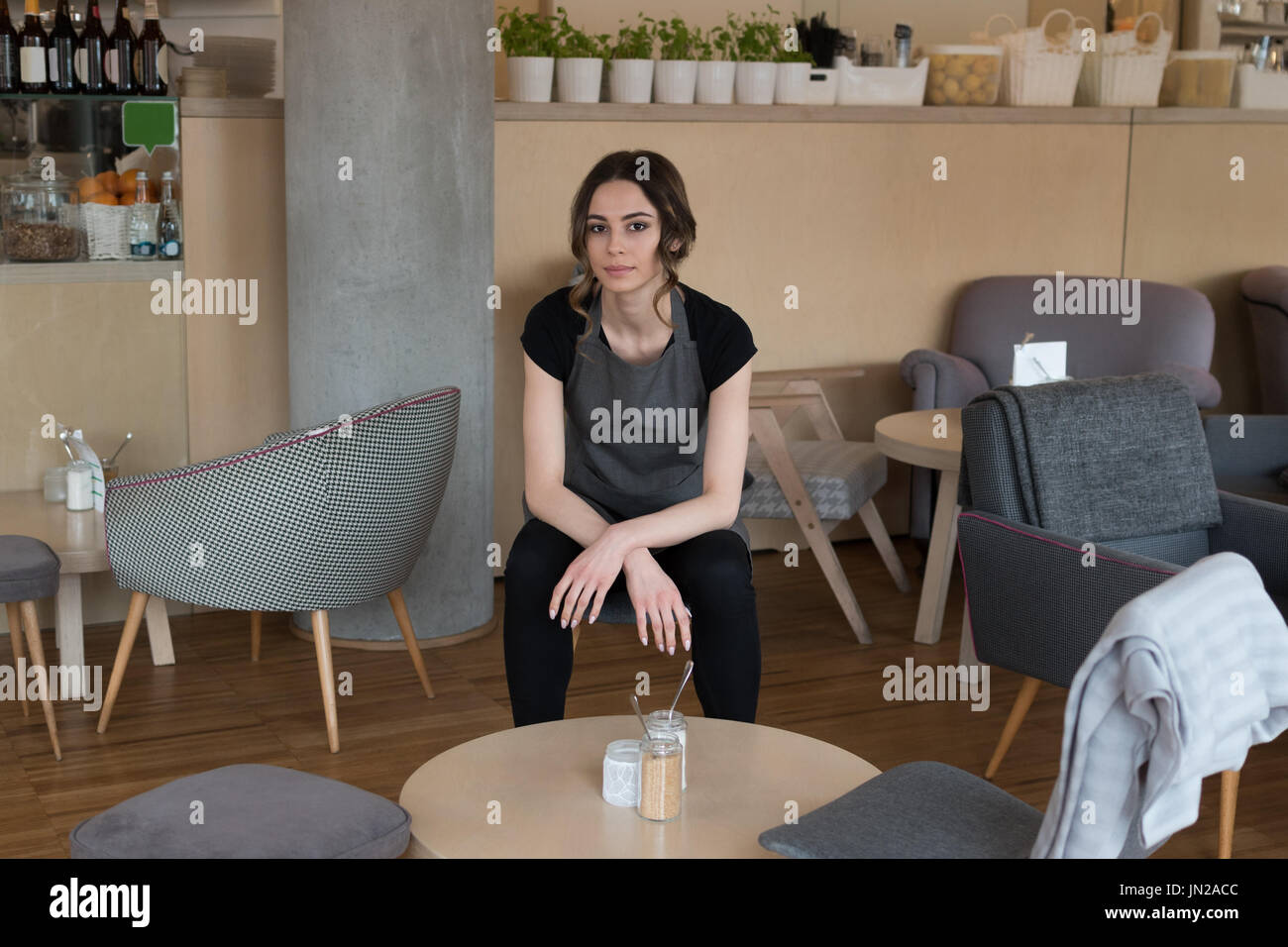 Portrait of female owner sitting on chair om cafe Stock Photo - Alamy