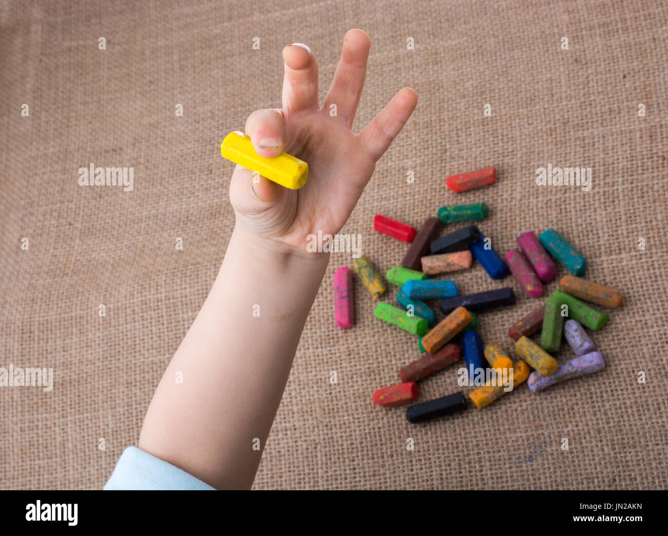 Used color crayons and a toddlers hand holding one Stock Photo - Alamy