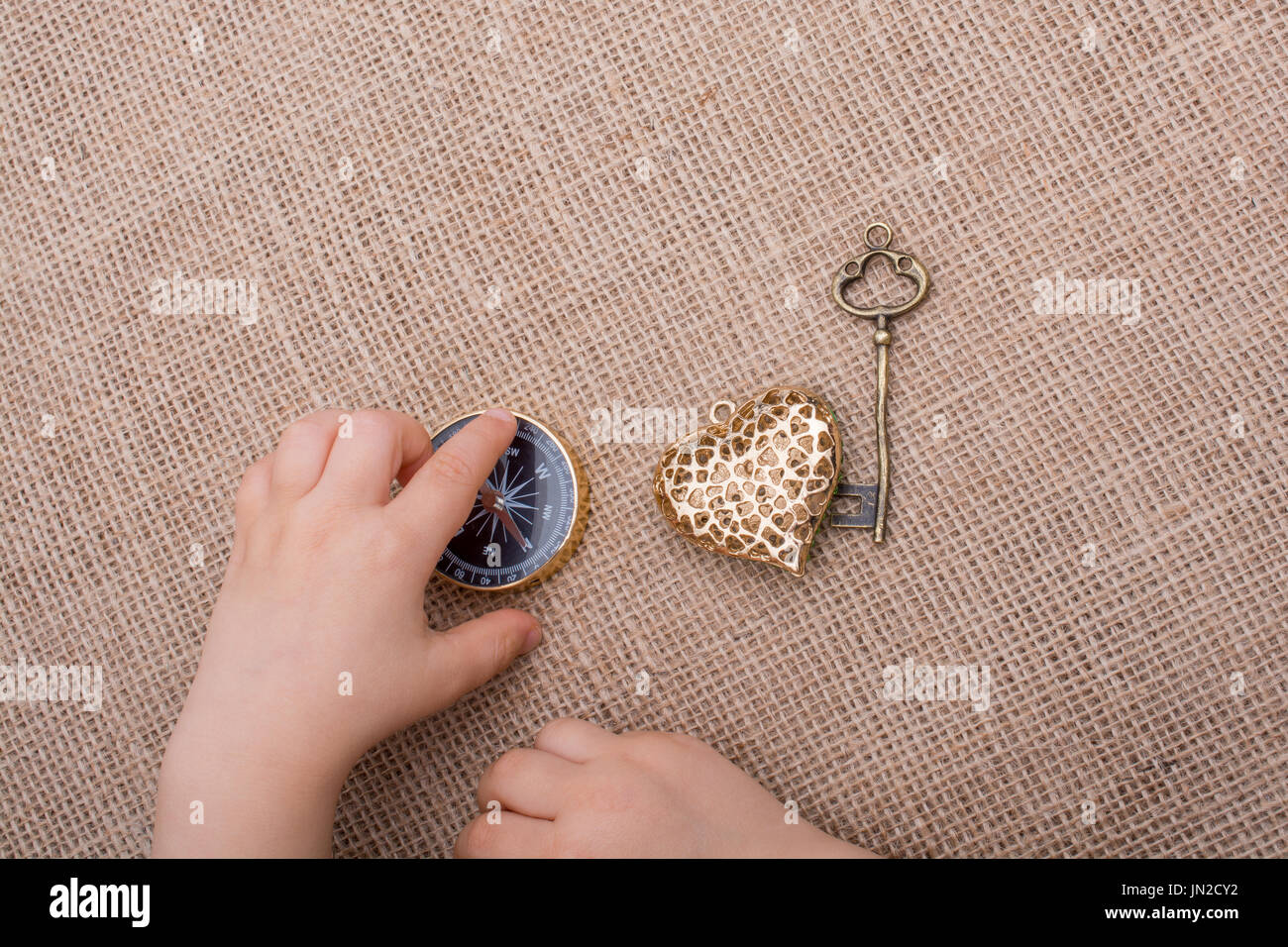 Compass, key and a heart shaped object beside a hand Stock Photo - Alamy