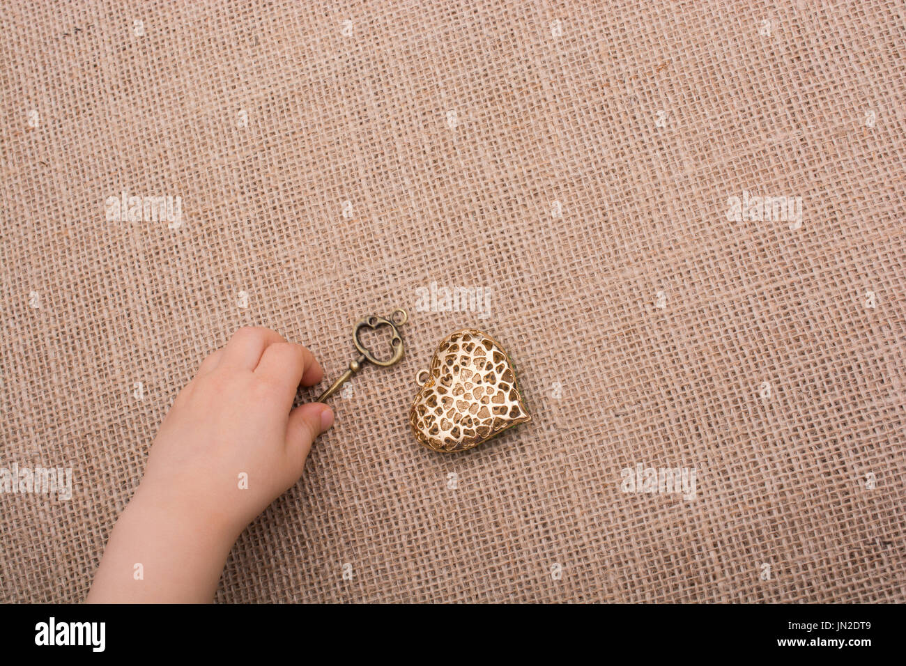 Heart shaped gold color metal object beside a hand Stock Photo - Alamy