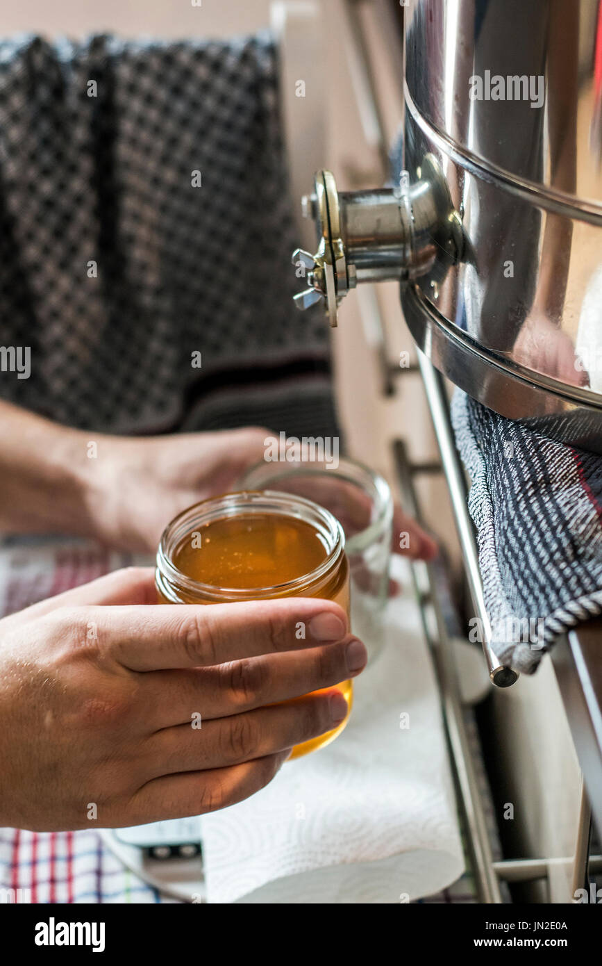 Beekeeper filling up the fresh new honey into glass jars on a scale ...