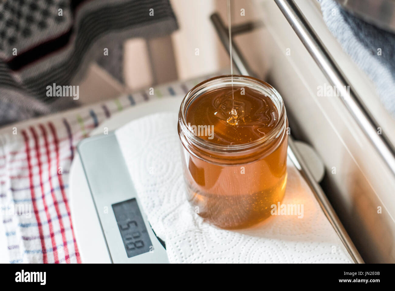 Beekeeper filling up the fresh new honey into glass jars on a scale ...
