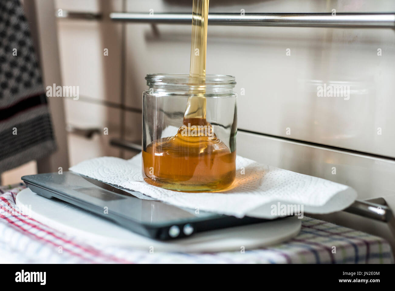 Beekeeper filling up the fresh new honey into glass jars on a scale ...