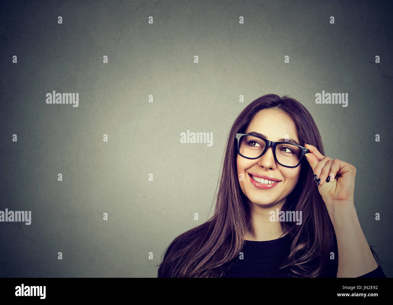 Pretty thinking woman in glasses looking up on gray background with ...