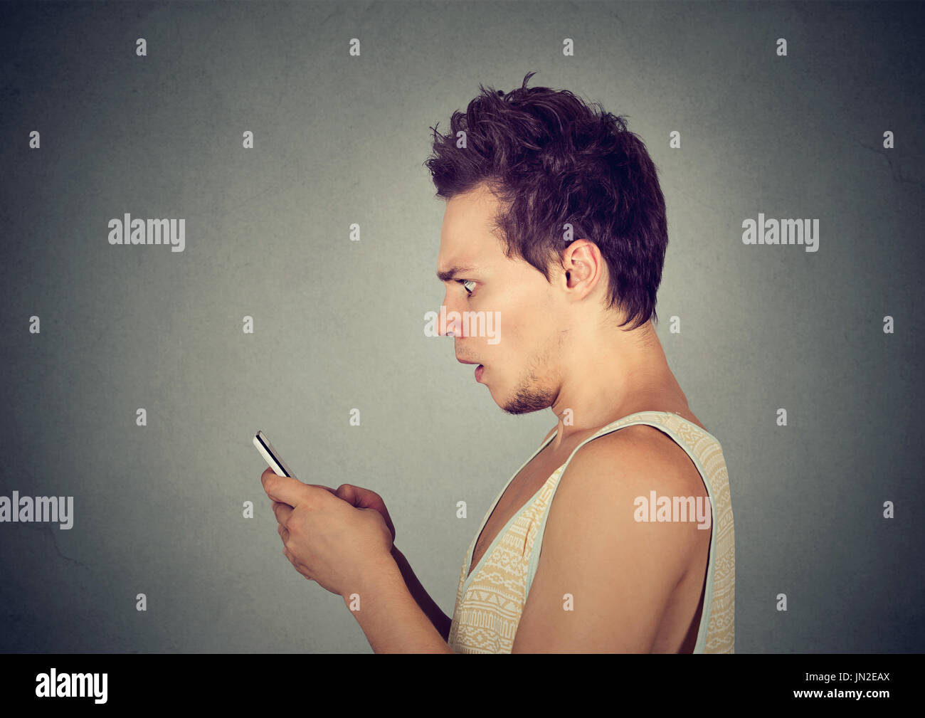 Side profile scared shocked young man holding looking at his mobile ...