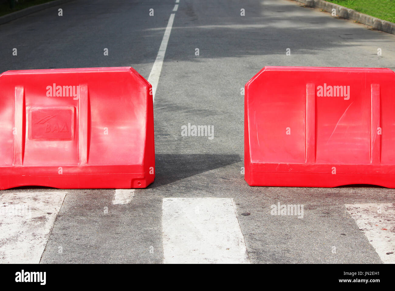Two red plastic barriers are blocking the road Stock Photo - Alamy