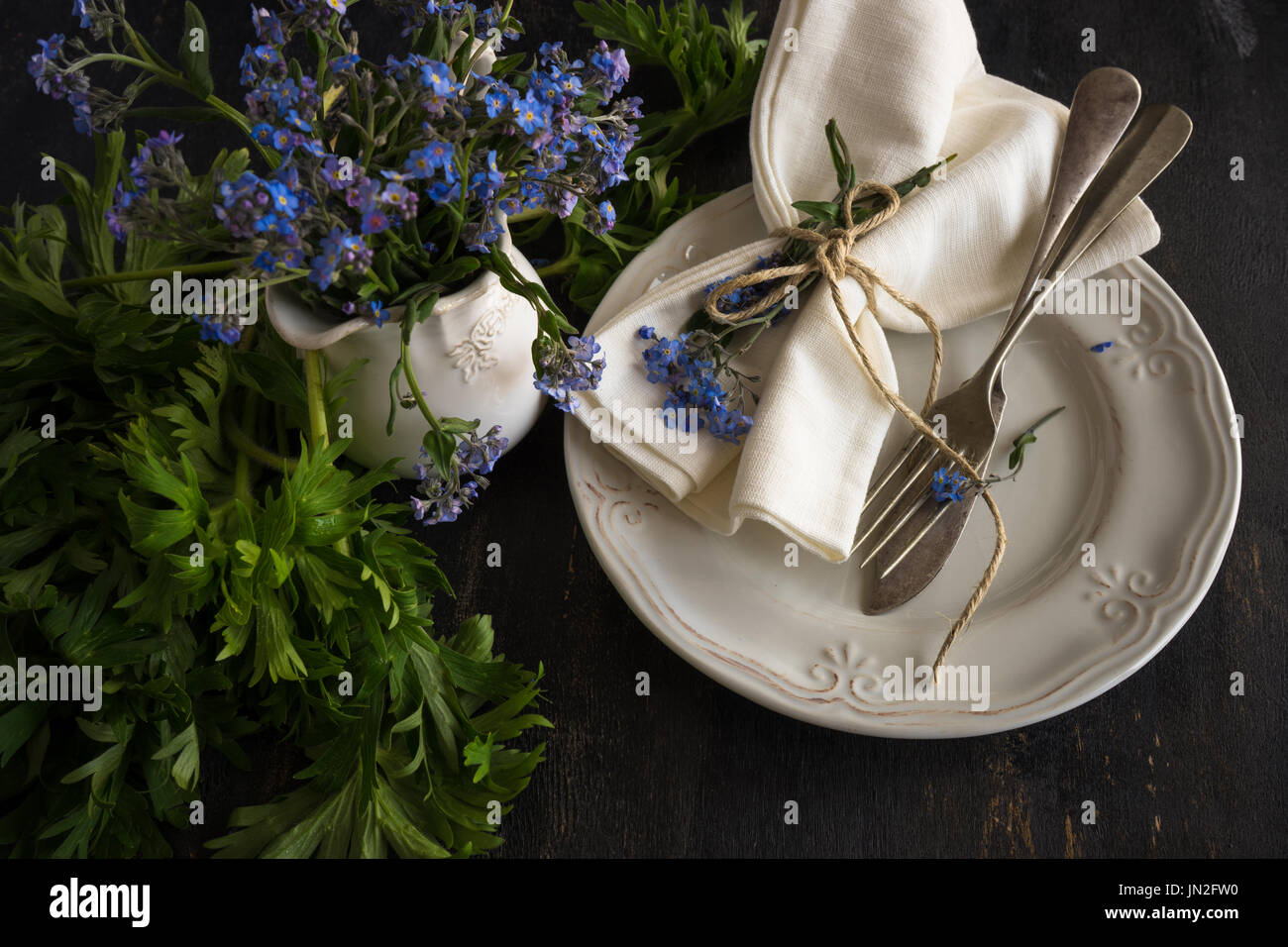 Summer floral table setting with bright blue forget-me-not flowers on ...