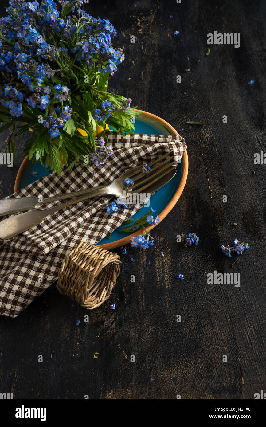 Summer floral table setting with bright blue forget-me-not flowers on ...