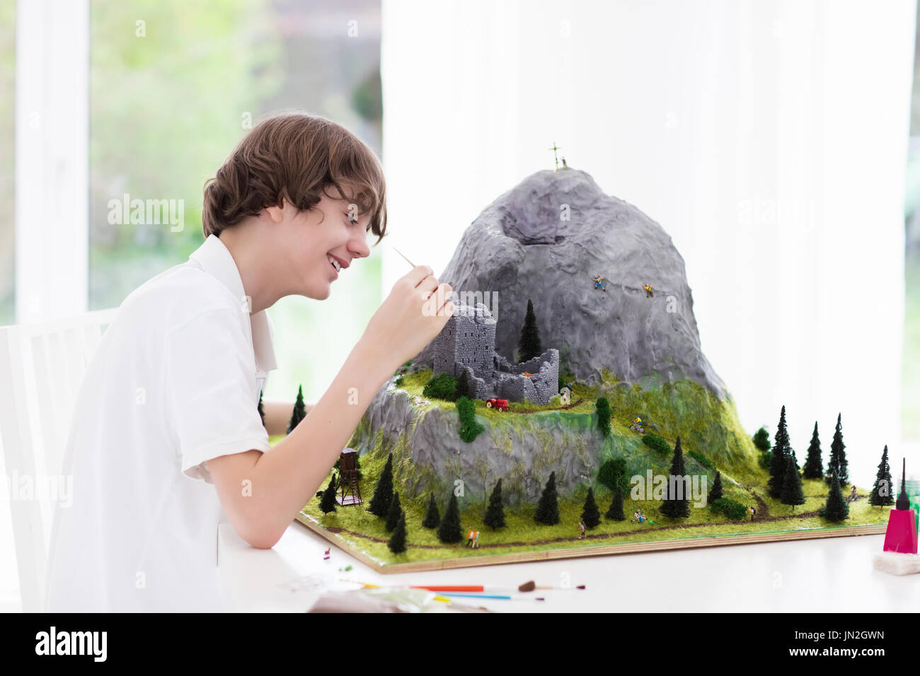 Teenager working on model building school project. Kids build miniature ...