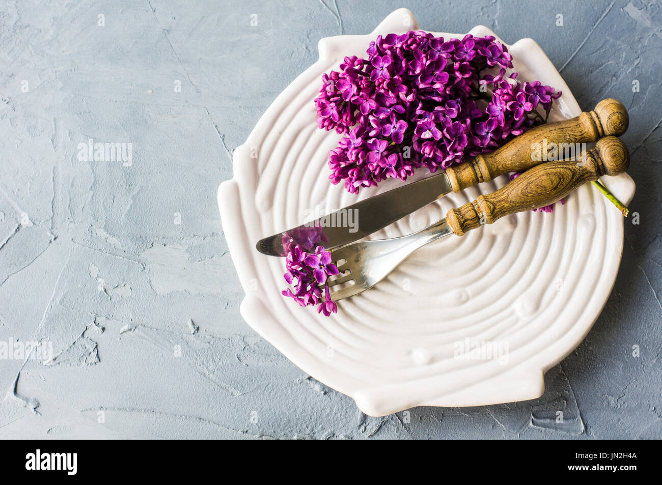 Spring table setting with bright lilac flowers on rustic background ...