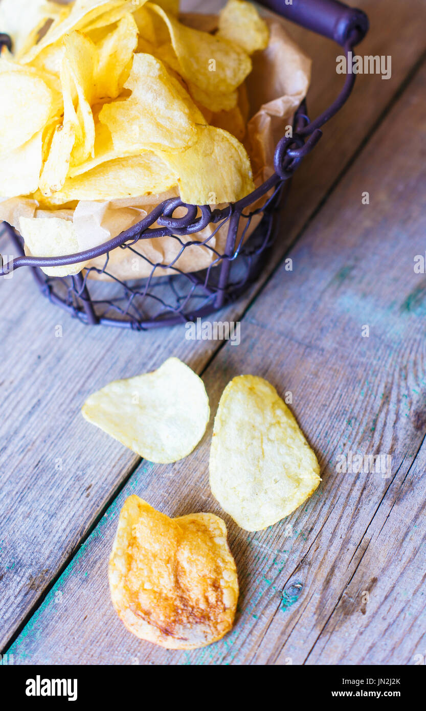 Crispy potato chips in rustic pot on old wooden table. Selective focus ...