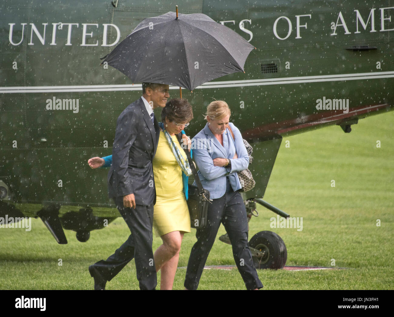United States President Barack Obama, left, holds the umbrella for ...
