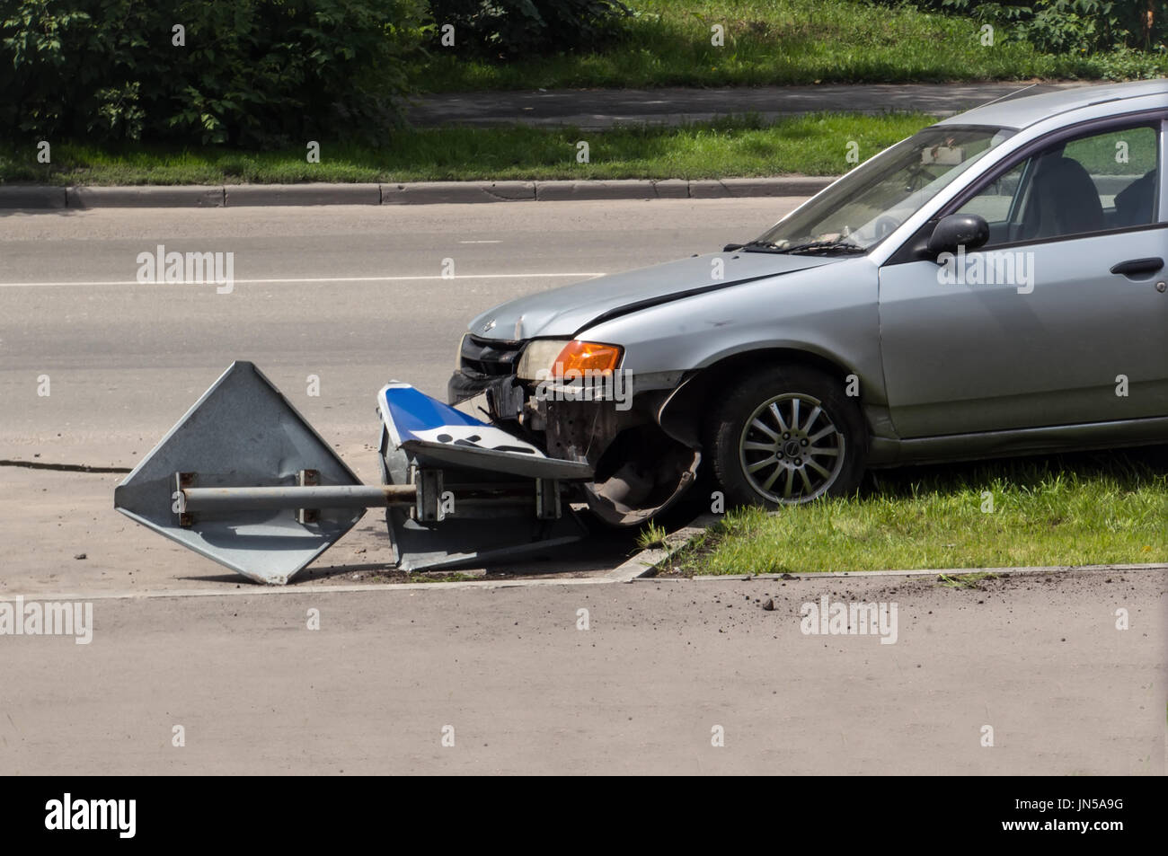 Broken crashed car on the street. Tilted road sign on a pedestrian ...