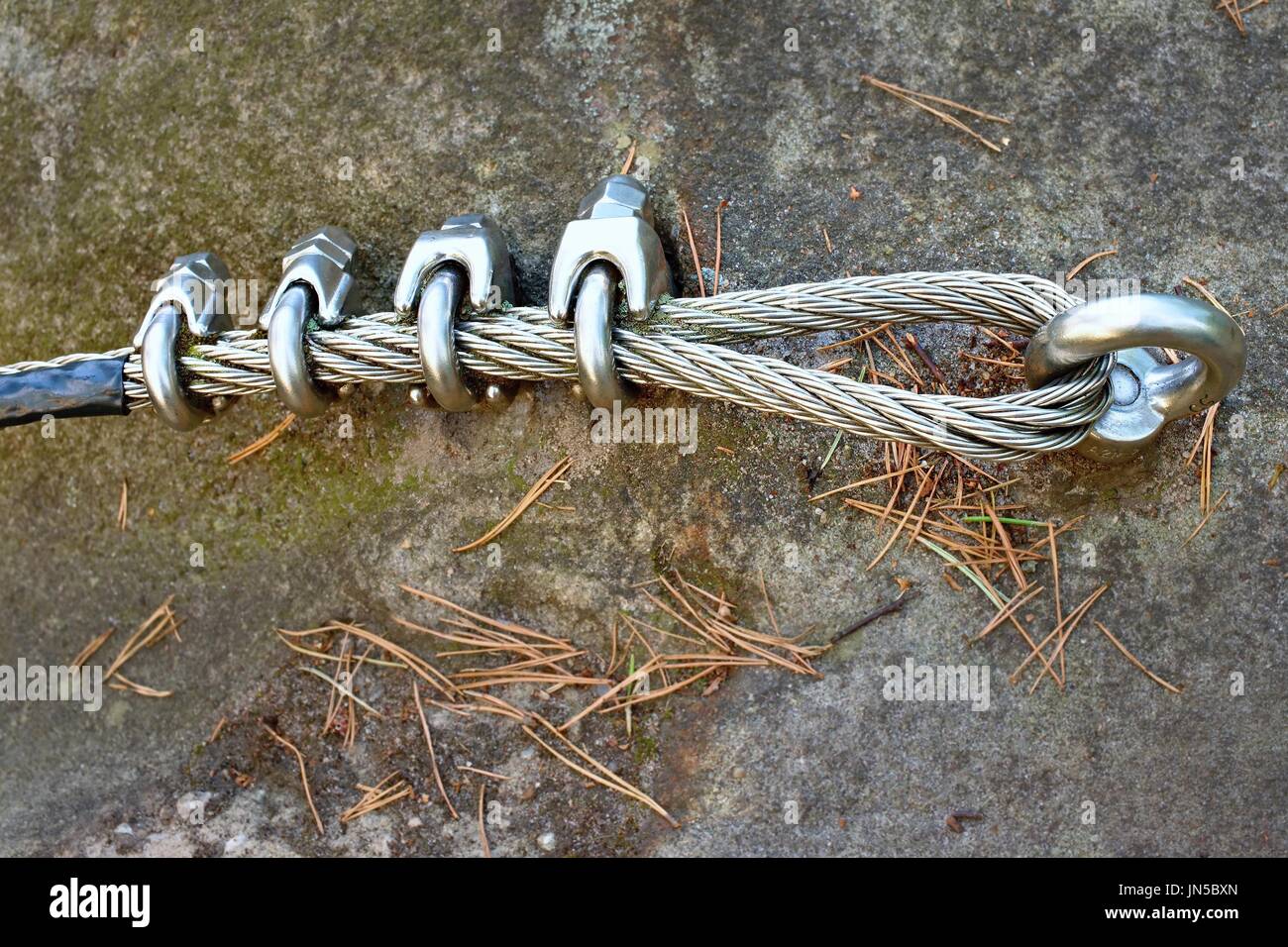 Mountain wall with carabine in the rock. End of the iron rope in loop ...