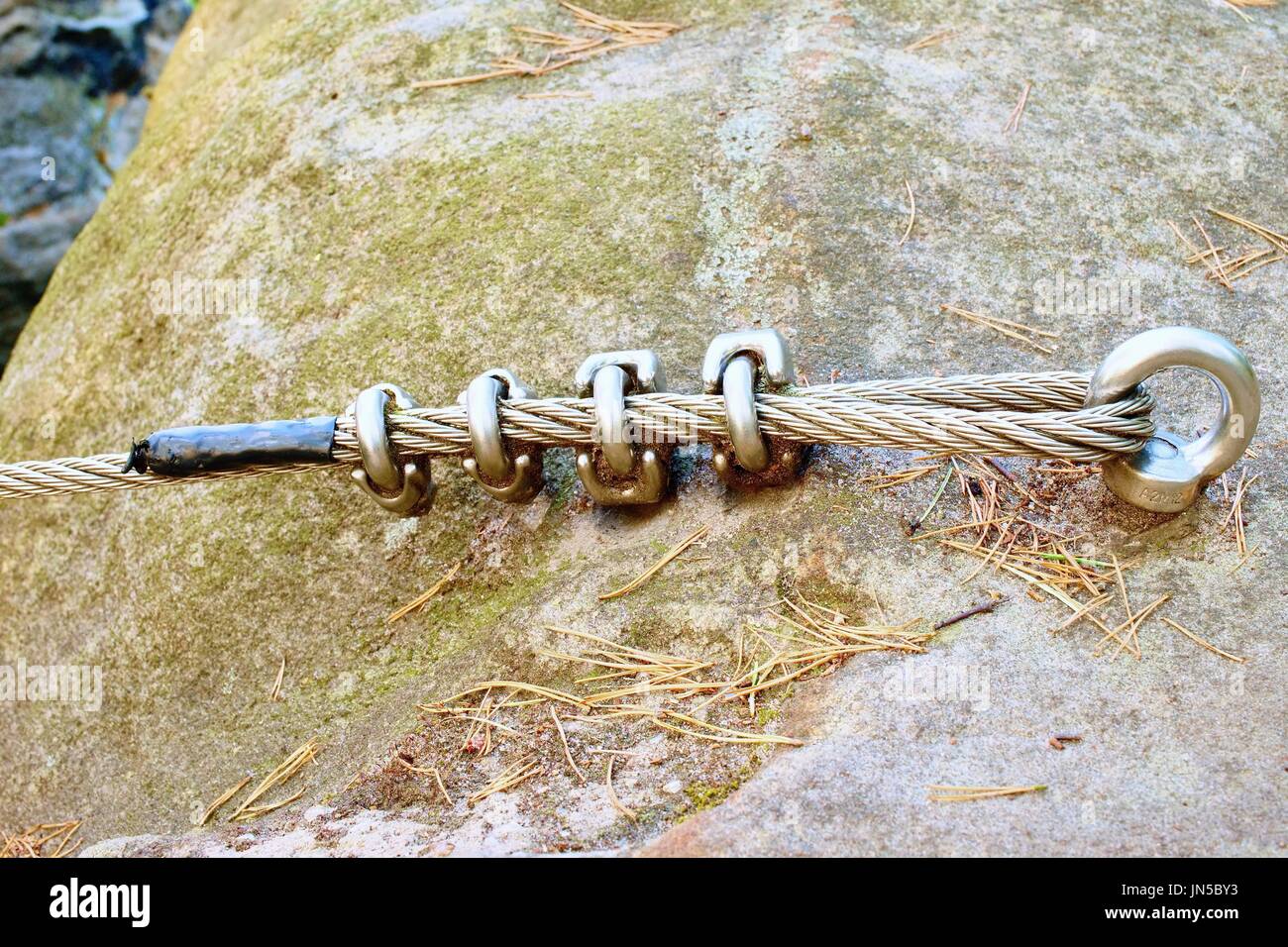 Mountain wall with carabine in the rock. End of the iron rope in loop ...
