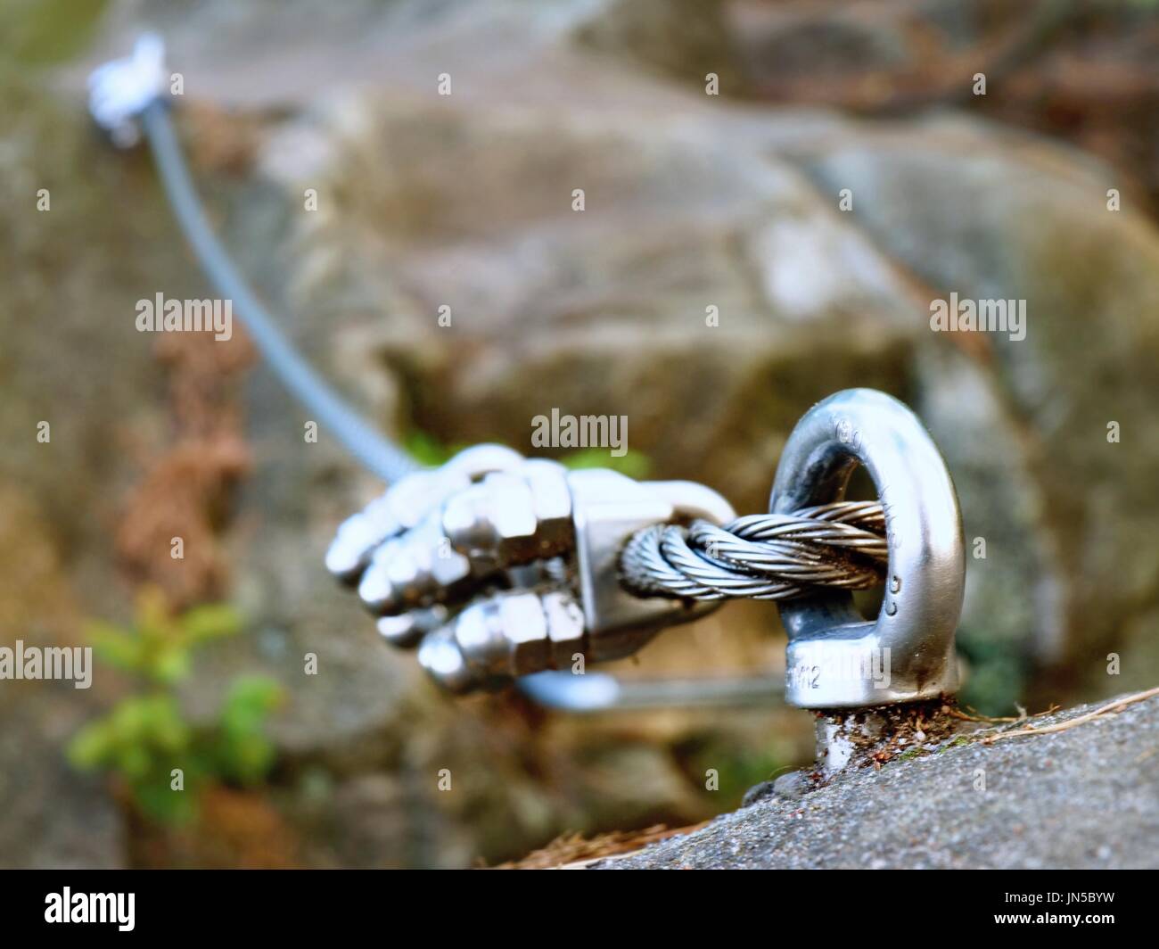 Iron twisted rope streched between rocks in climbers patch. Rope fixed ...