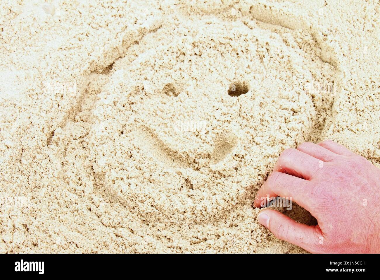 Hand paint smiley face in summer beach sand Stock Photo - Alamy
