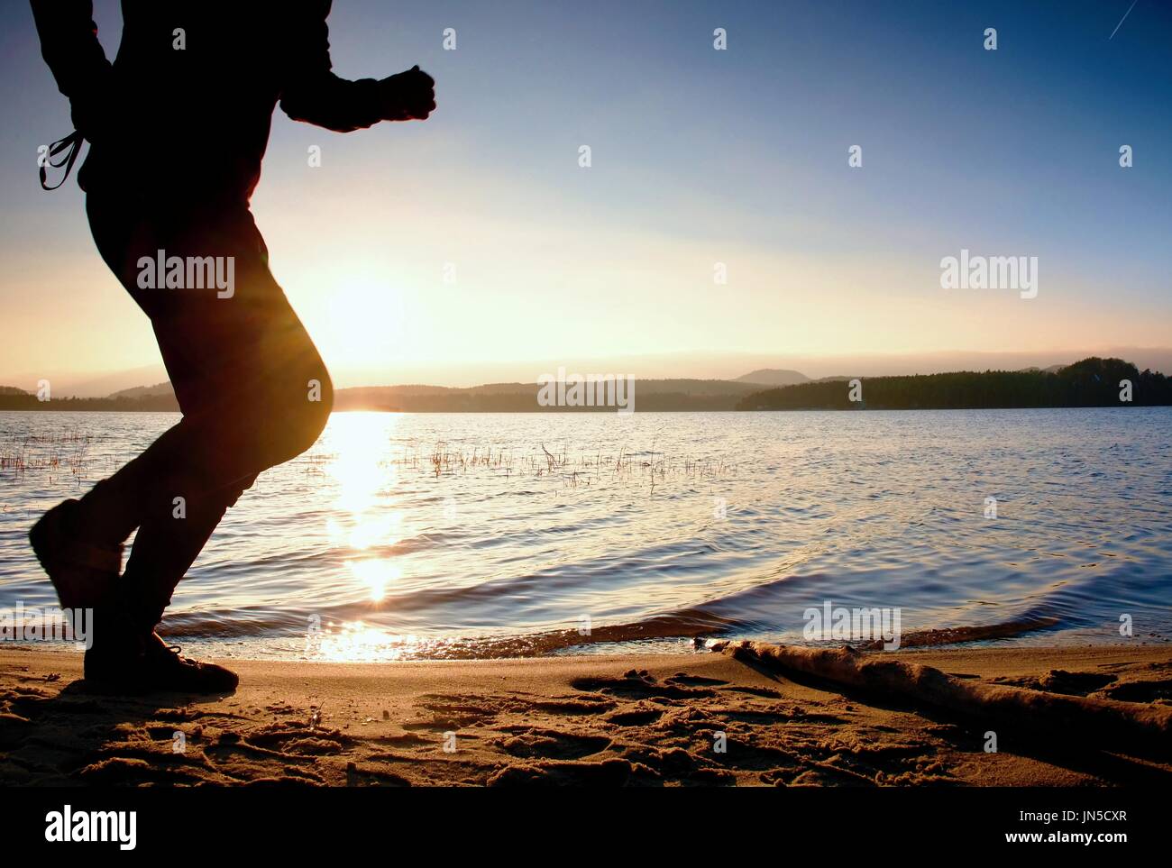 Silhouette of sport active man running and exercising on coastline at ...