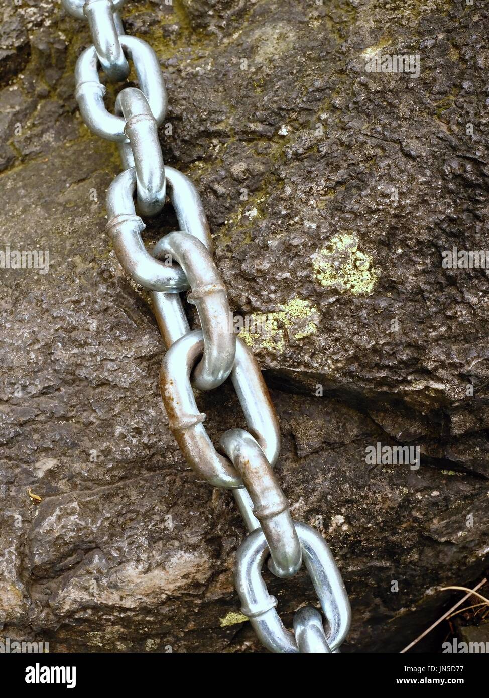 Detail of chain and steel bolt anchor eye in sandstone rock. The end ...