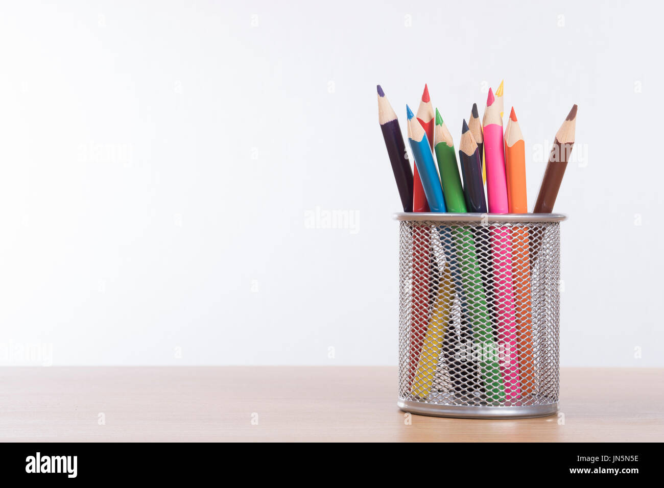 Wire mesh basket full of colorful pencil crayons in a concept of art ...