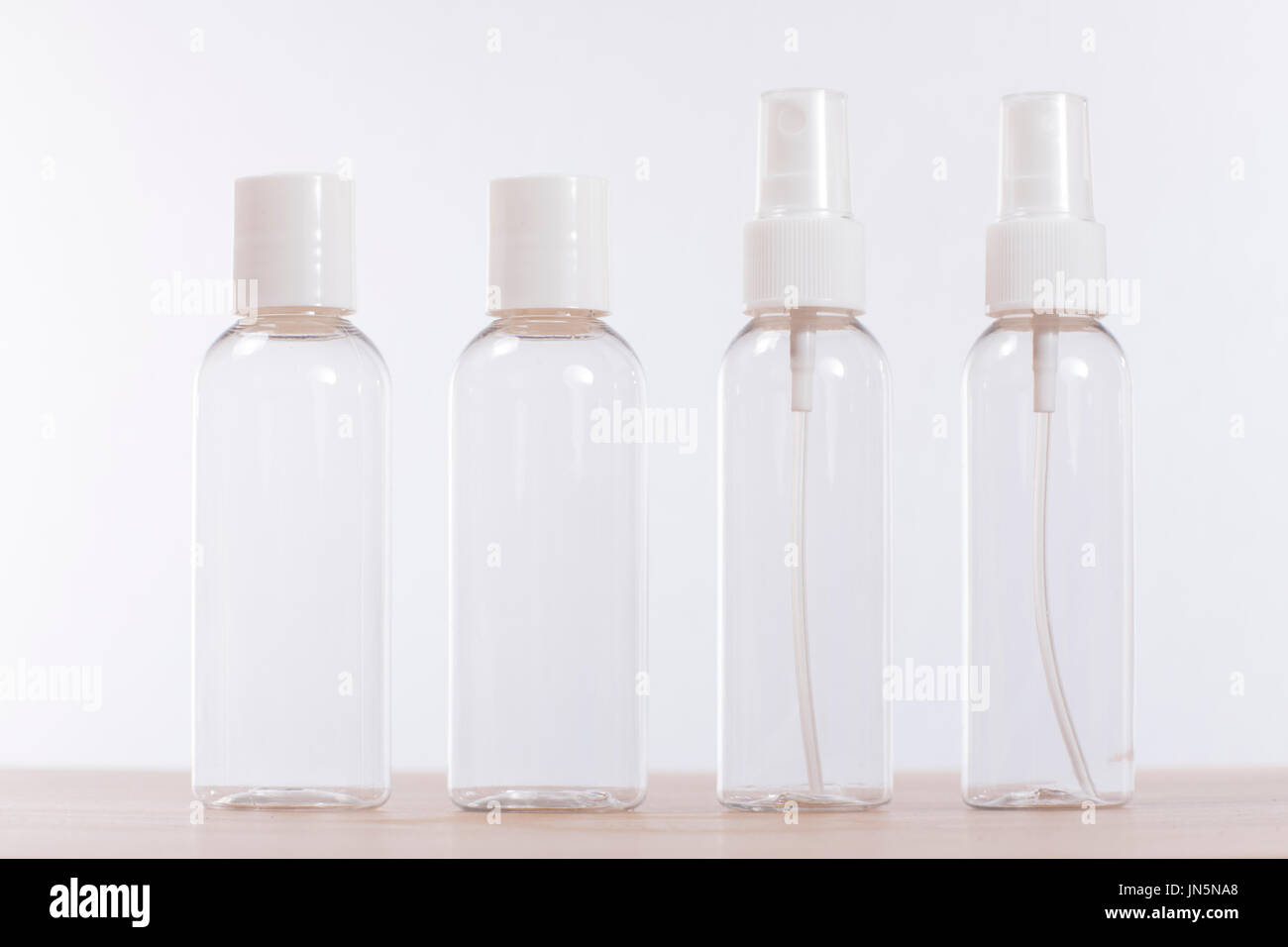 Two empty clear plastic shampoo bottles and two spray bottles on a ...