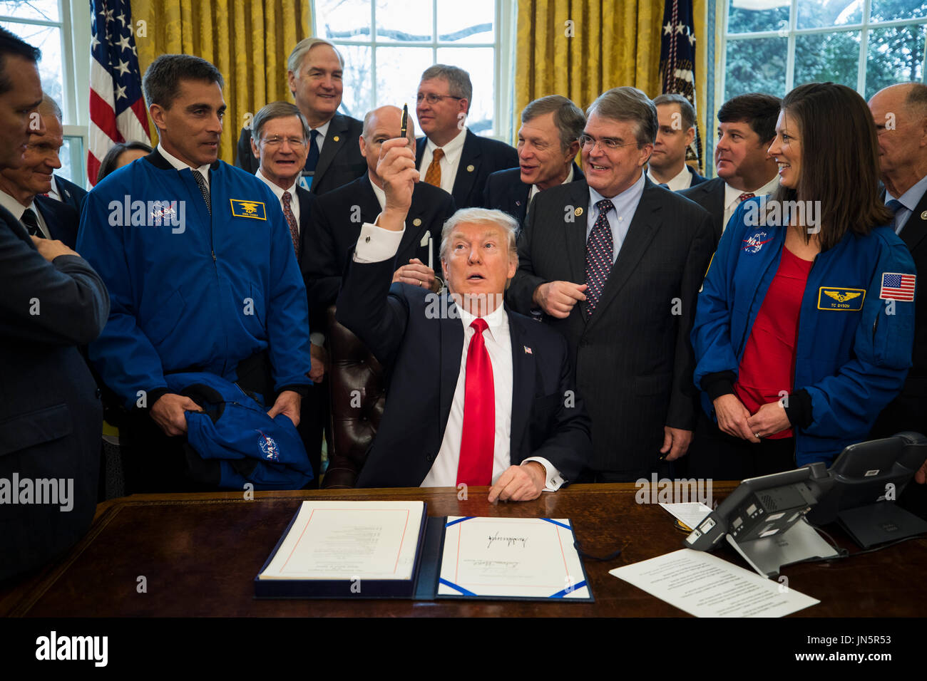U.S. President Donald J. Trump hands out pens after signing the NASA ...