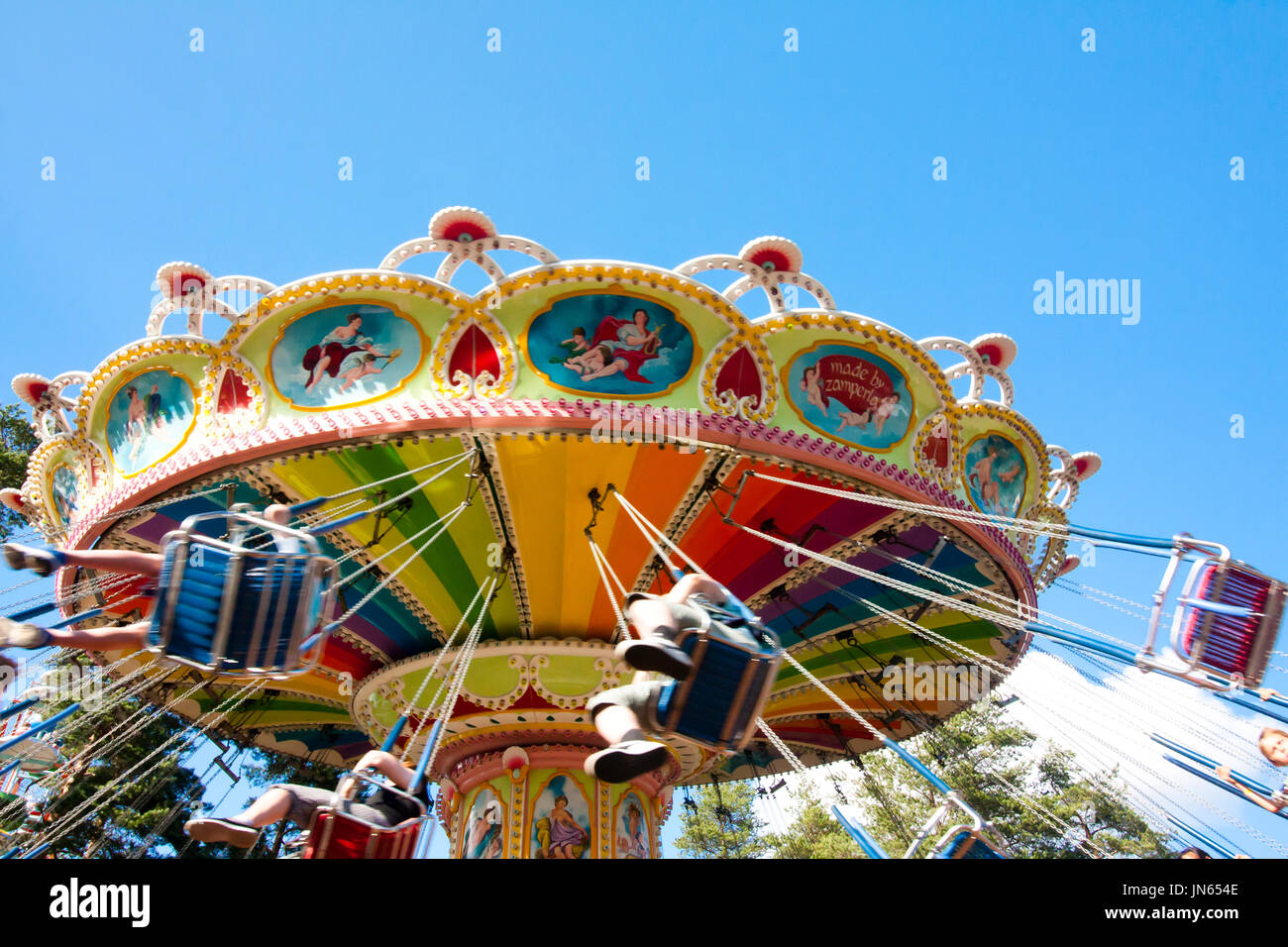 Colorful chain swing carousel in motion at amusement park on blue sky ...