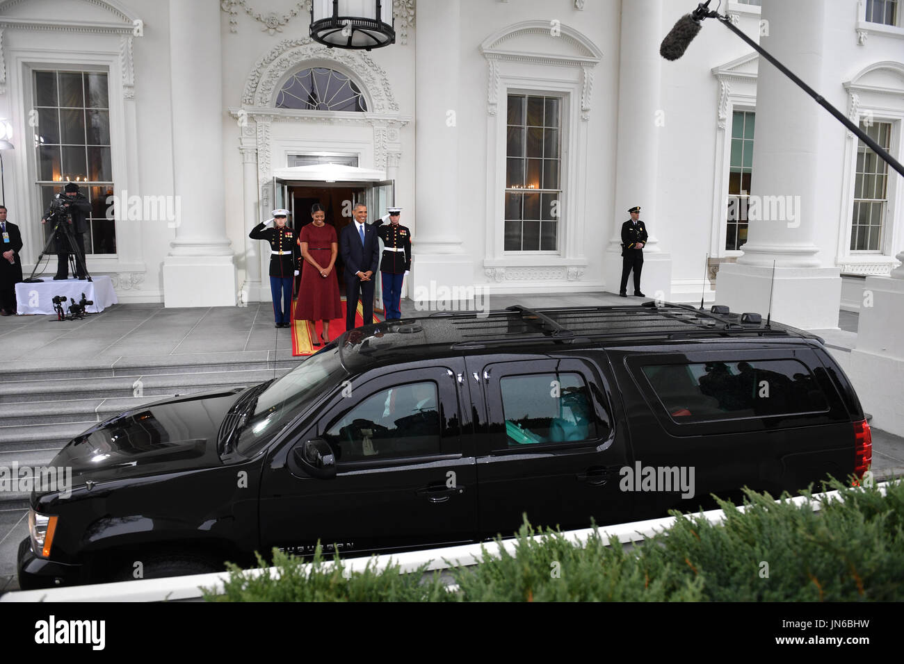 President Barack Obama (R) and Michelle Obama wait as the car carrying ...