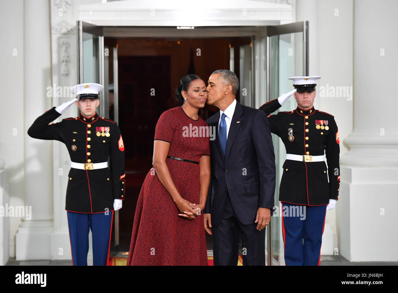 President Barack Obama (R) gives Michelle Obama a kiss as they wait for ...