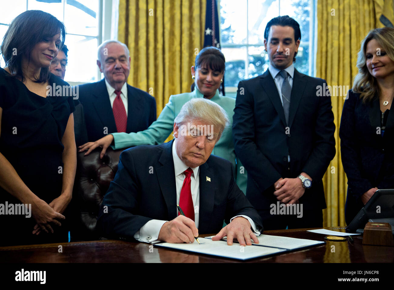 U.S. President Donald Trump signs an executive order surrounded by ...