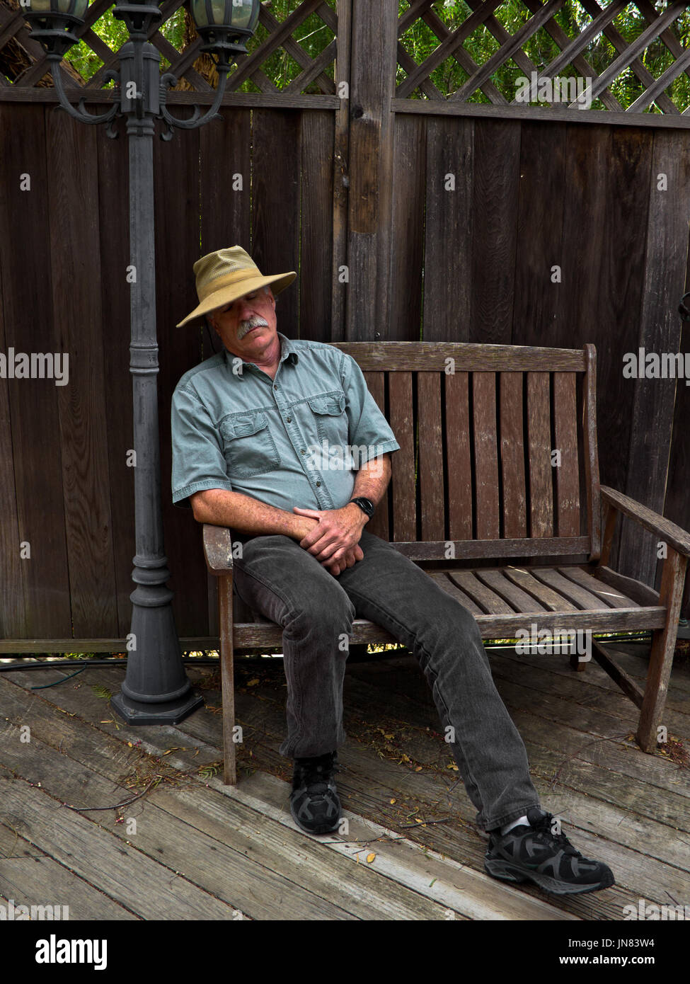 A man in a hat naps on a bench Stock Photo - Alamy