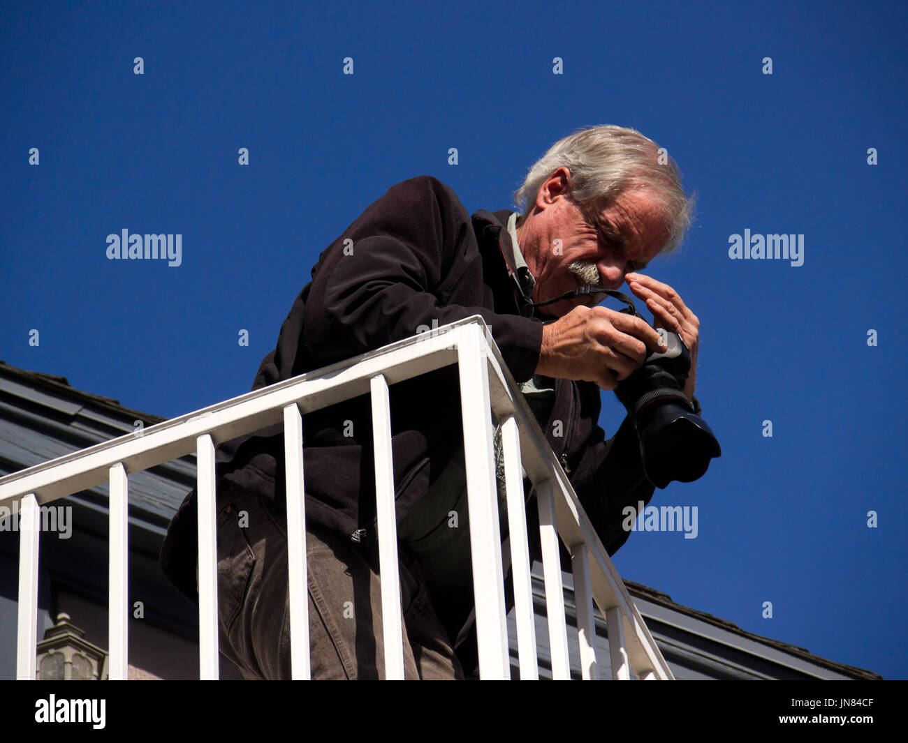A man stands on a balcony photographing Stock Photo - Alamy