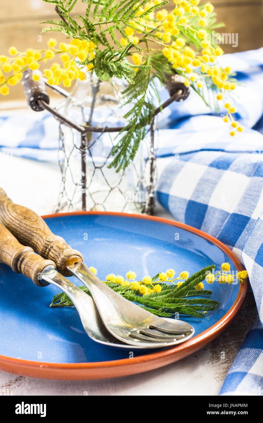 Spring festive dining table setting with yellow mimosa flowers, napkins ...